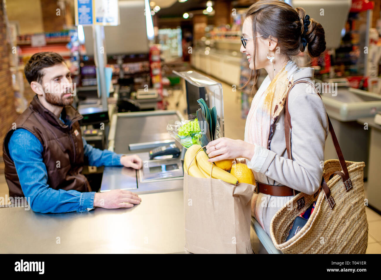 Young woman customer buying food, standing on the cash register with ...