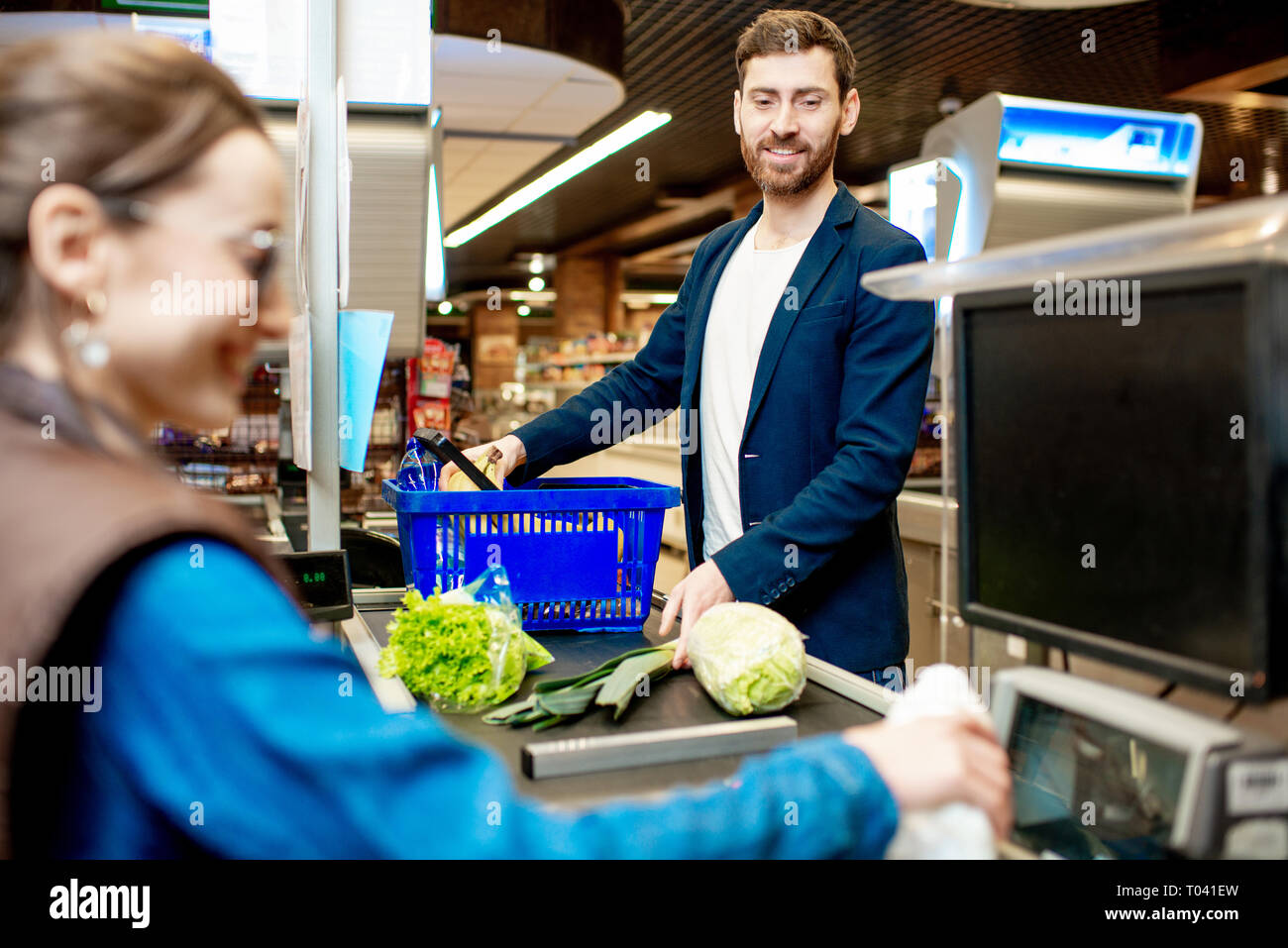 Handsome businessman putting products on the cash register buying food ...