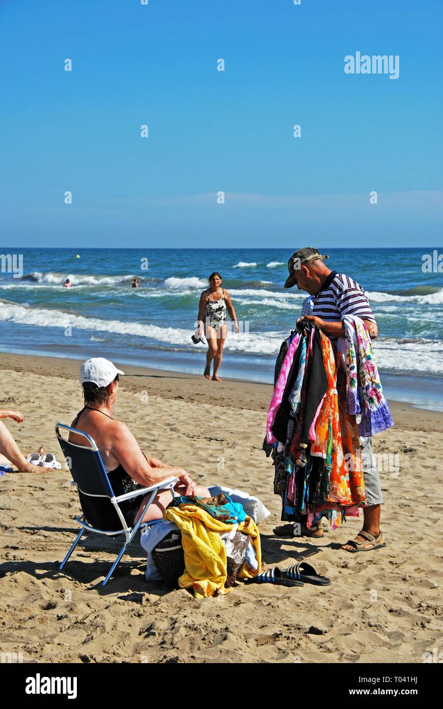 Beach trader showing his goods to a tourist on Playa de la Vibora beach ...