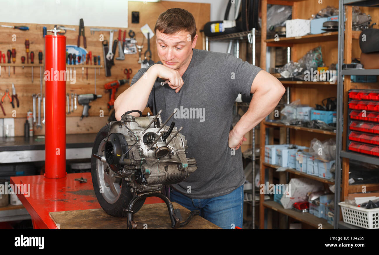 Man mechanic is puzzled in time repairing modern moto and looking on ...