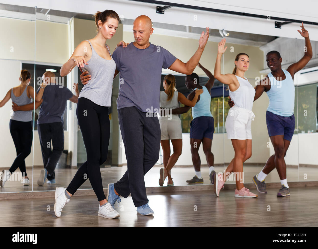 Young positive people practicing vigorous jive movements in dance ...