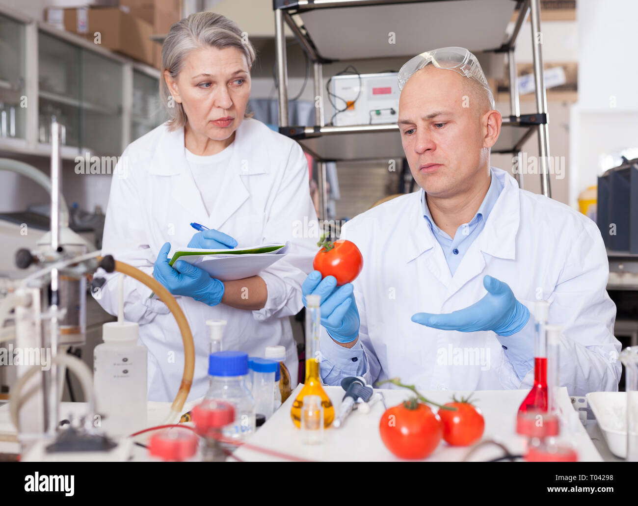 Two professional genetic scientists working in laboratory, taking notes ...