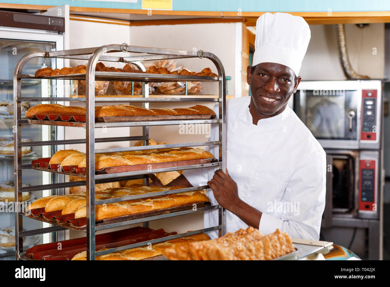 Professional baker working behind counter in bakeshop, pushing steel ...