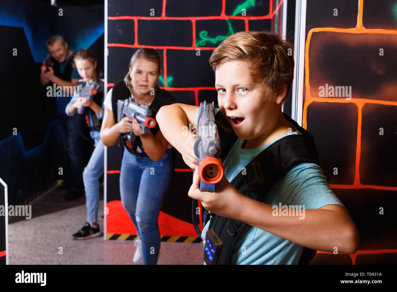 Excited glad cheerful positive smiling boy aiming laser gun at other ...