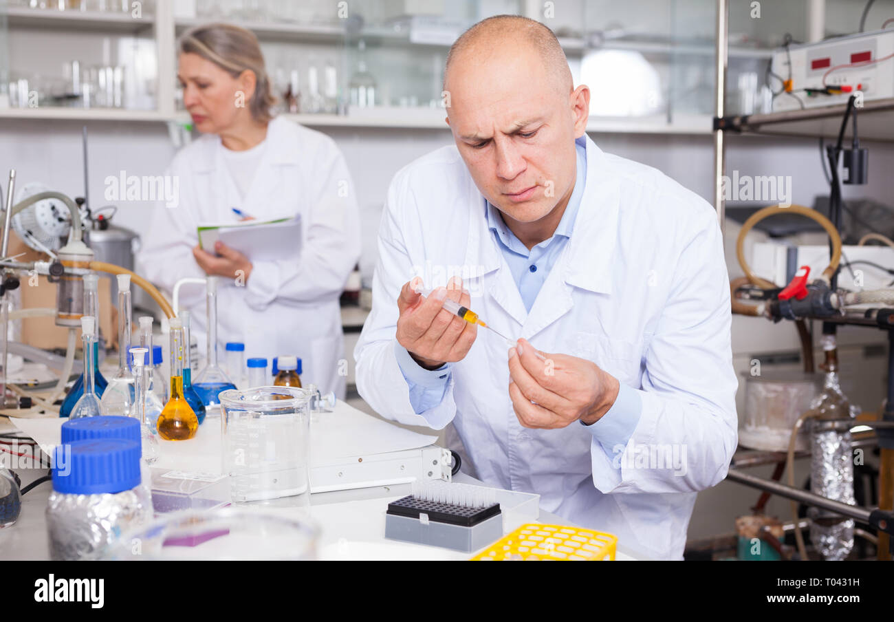 Professional biochemist performing experiments in lab room, mixing and ...