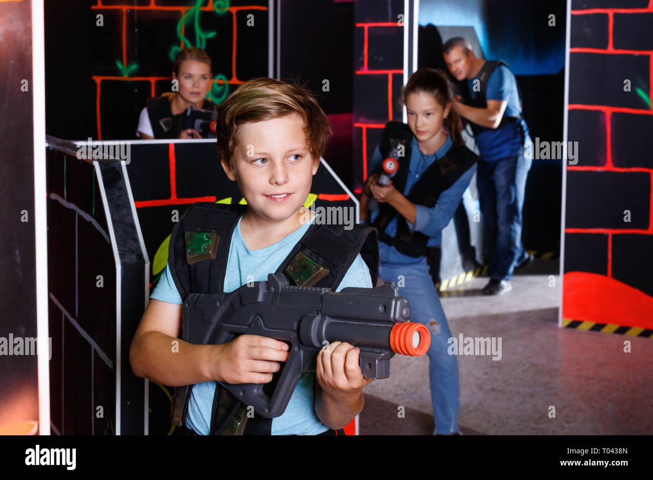 Excited glad cheerful smiling boy aiming laser gun at other players ...