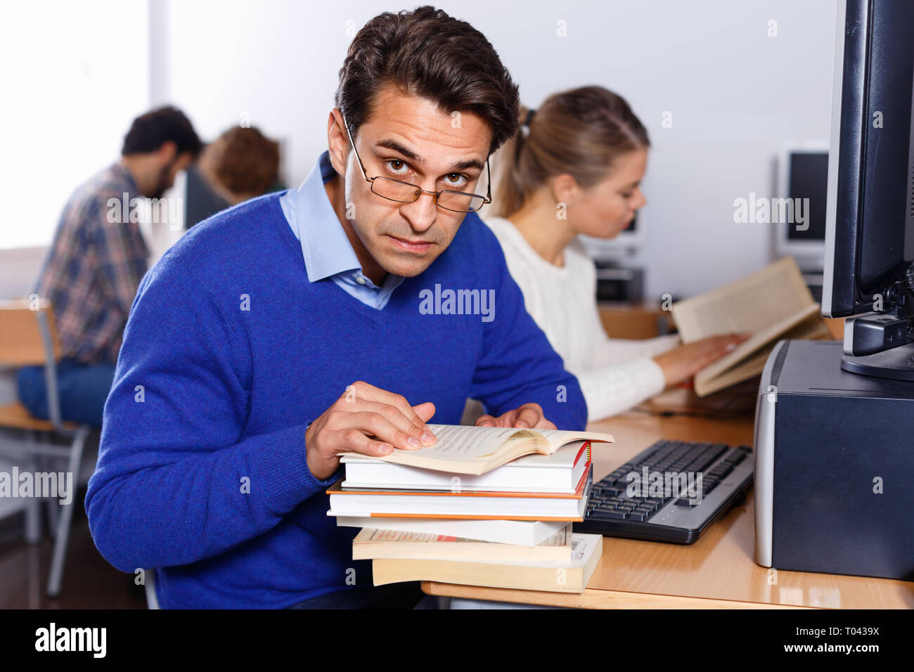 Serious cheerful positive adult student reading textbooks while ...