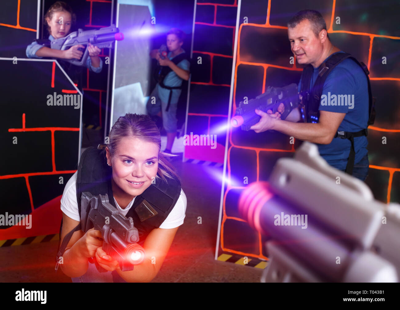 attractive girl with laser pistol playing laser tag with friends on ...