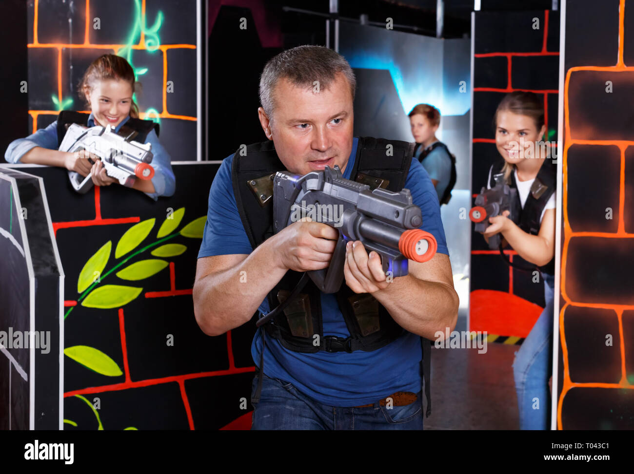 Emotional man with laser pistol playing laser tag with his family in a ...