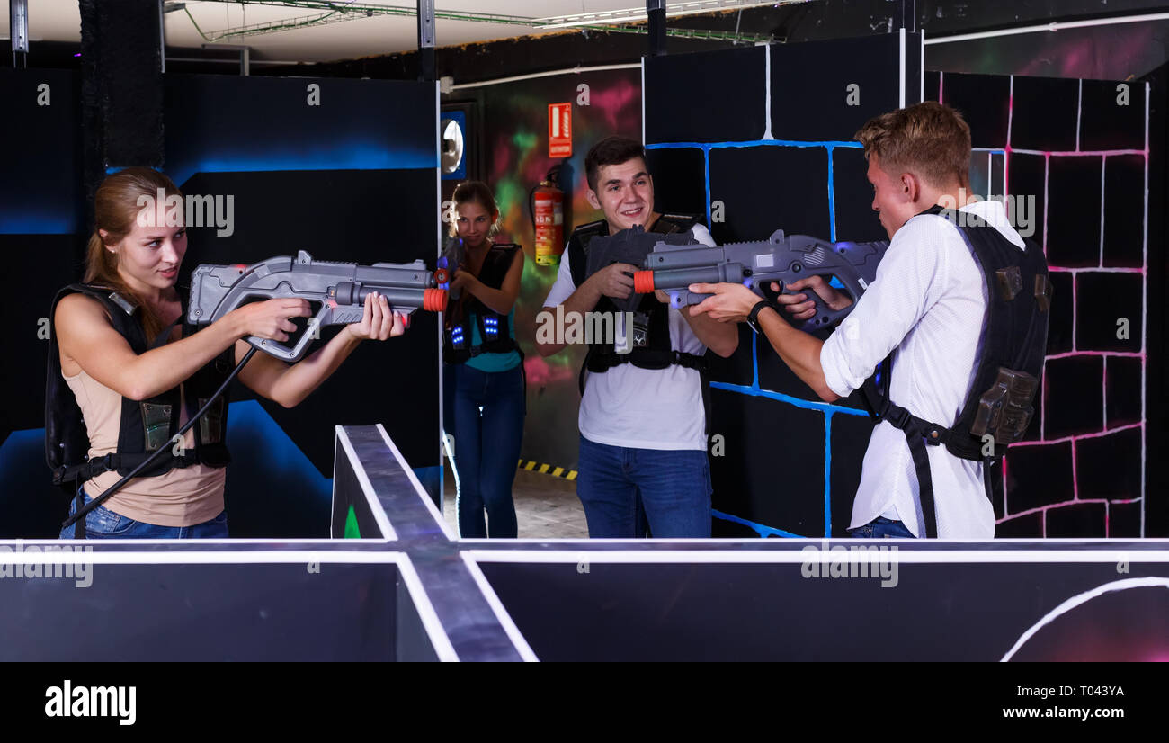 Smiling guys and girls with laser pistols in their hands playing ...