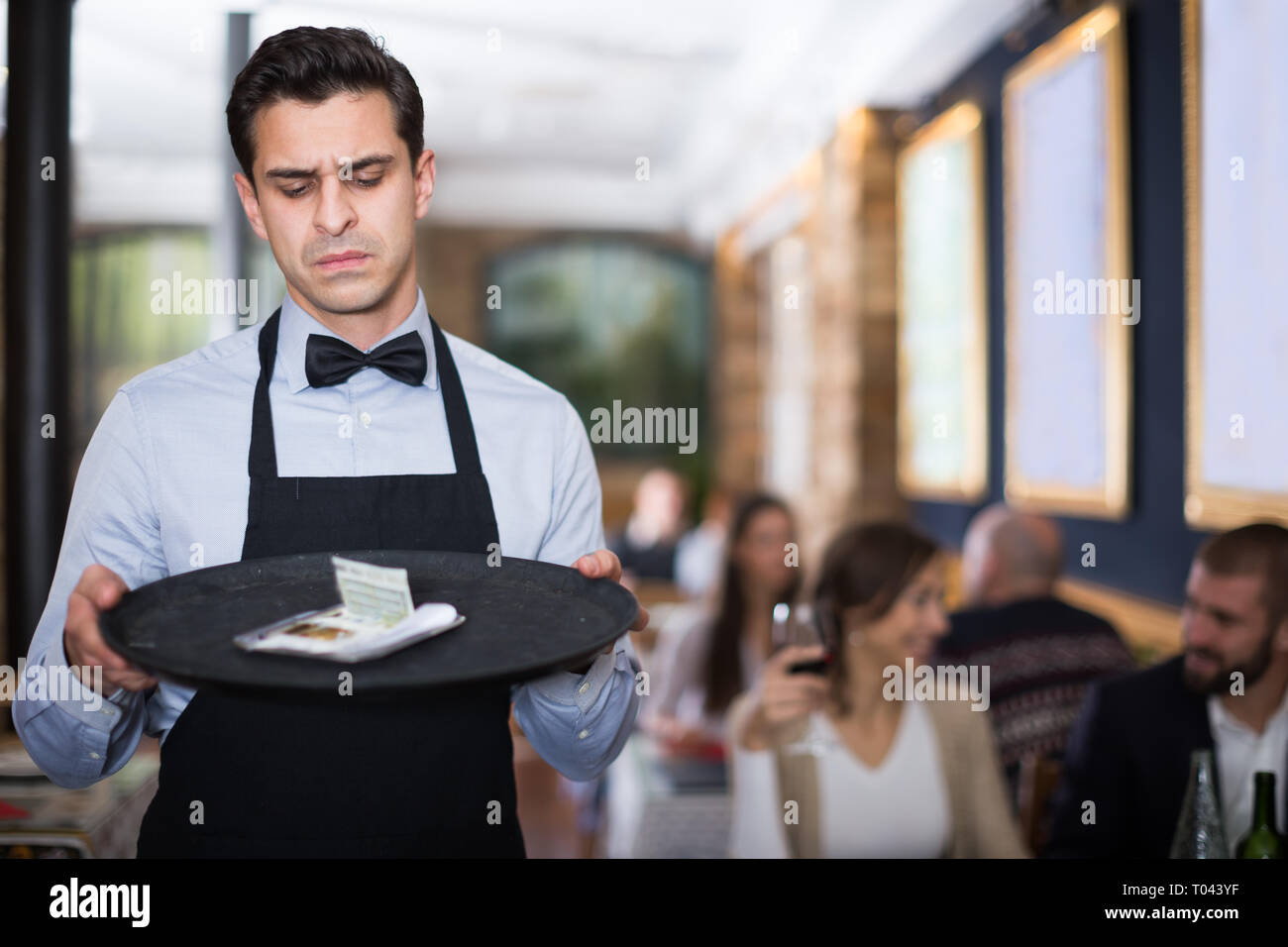frustrated waiter looking at a tip on a tray in a cafe Stock Photo - Alamy