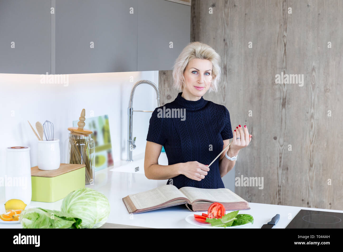 young blond woman cooking in modern kitchen Stock Photo - Alamy