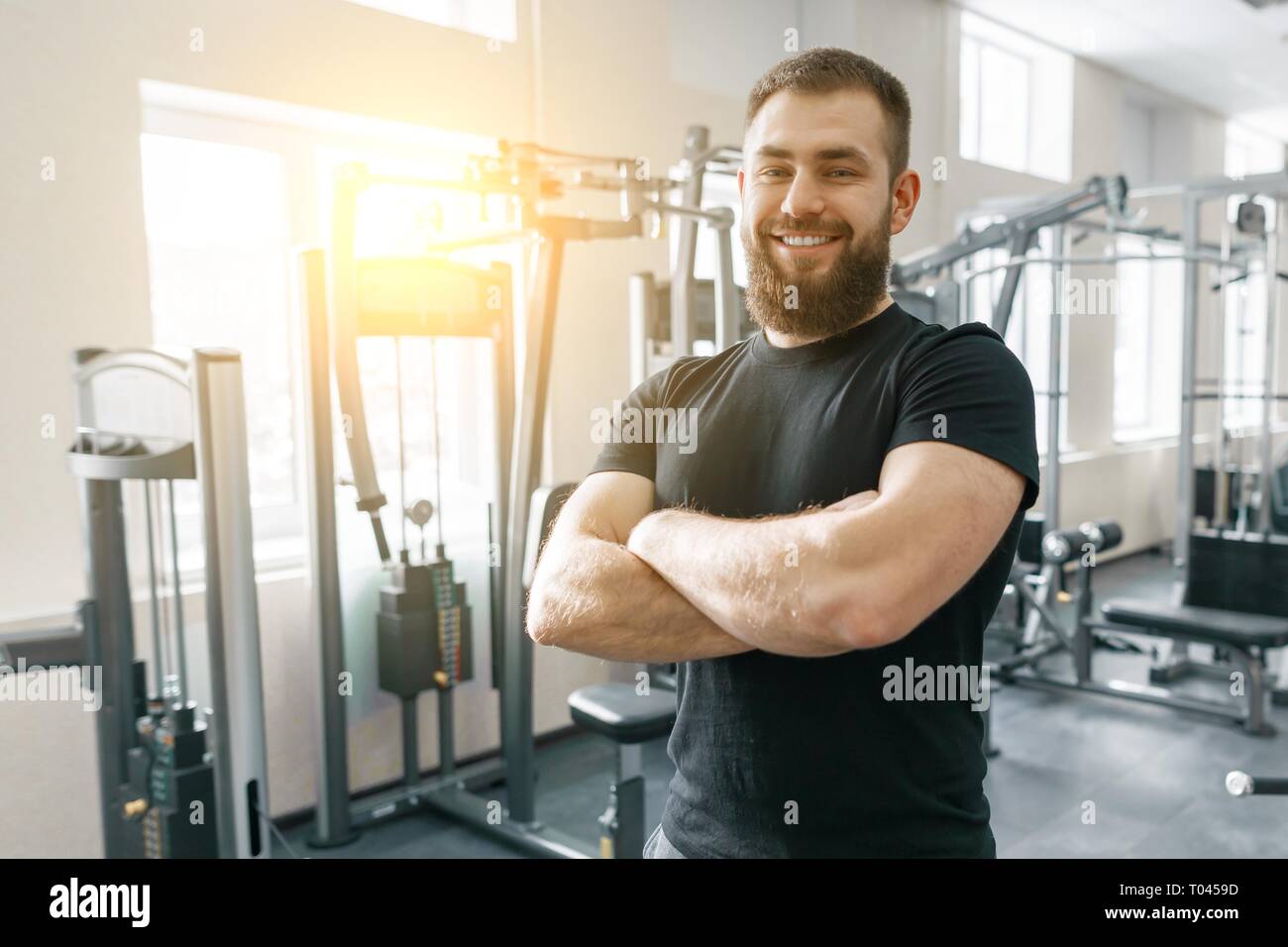 Portrait of smiling personal fitness trainer in gym, confident man with ...