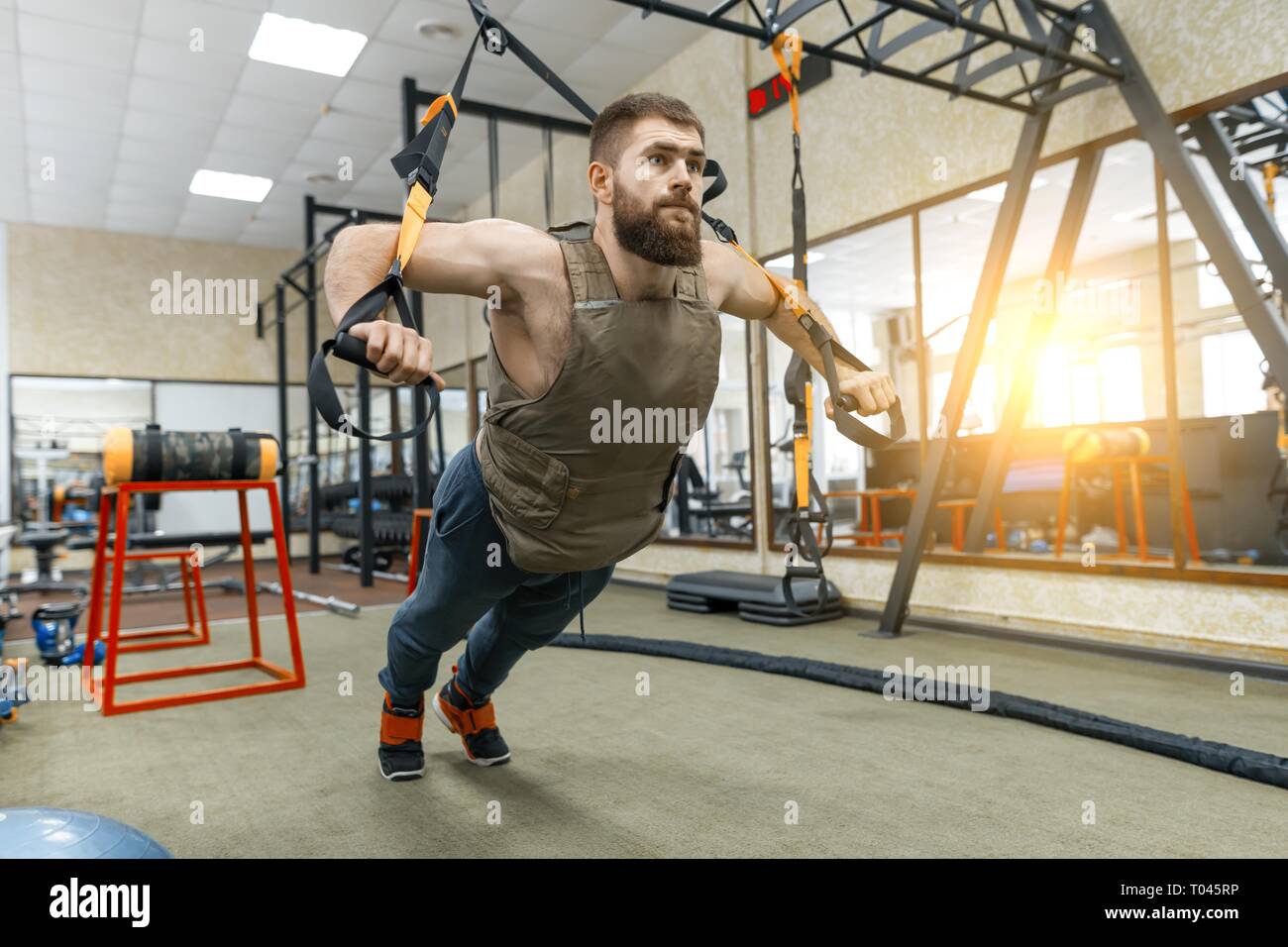Muscular bearded man dressed in military weighted armored vest doing ...
