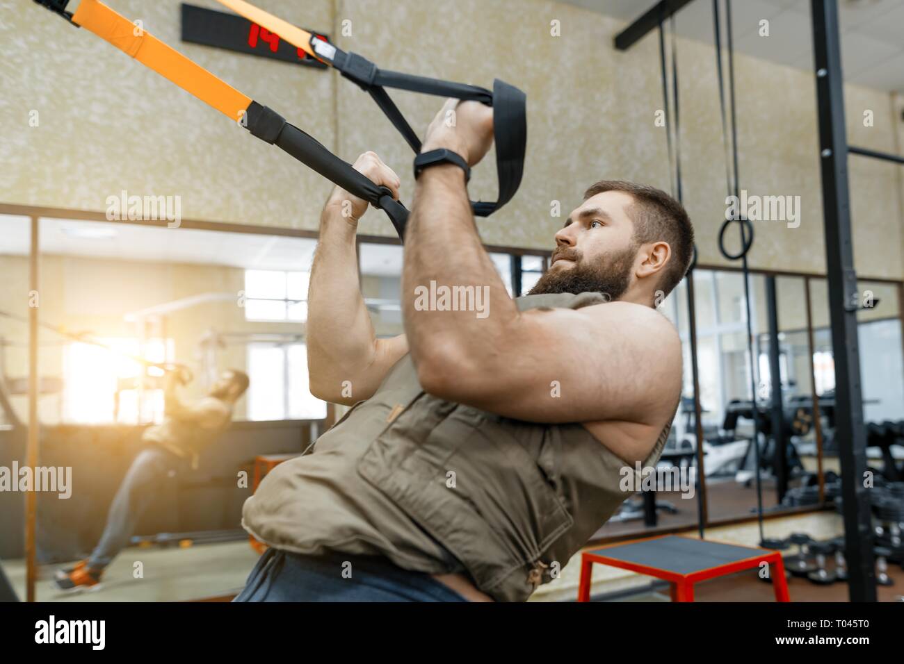 Muscular bearded man dressed in military weighted armored vest doing ...