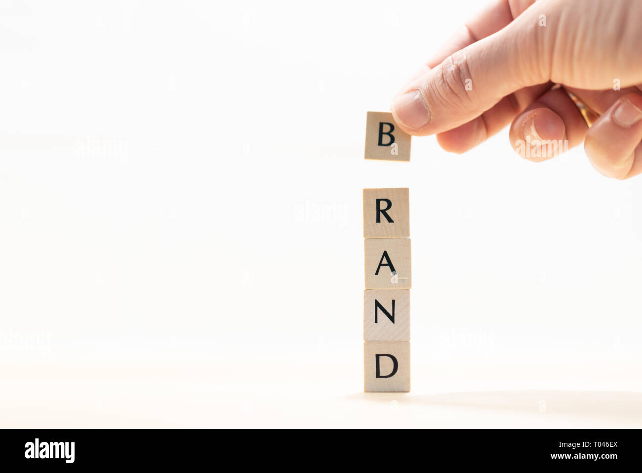The hand of a man forms the word "BRAND" with wooden letters. Symbol ...