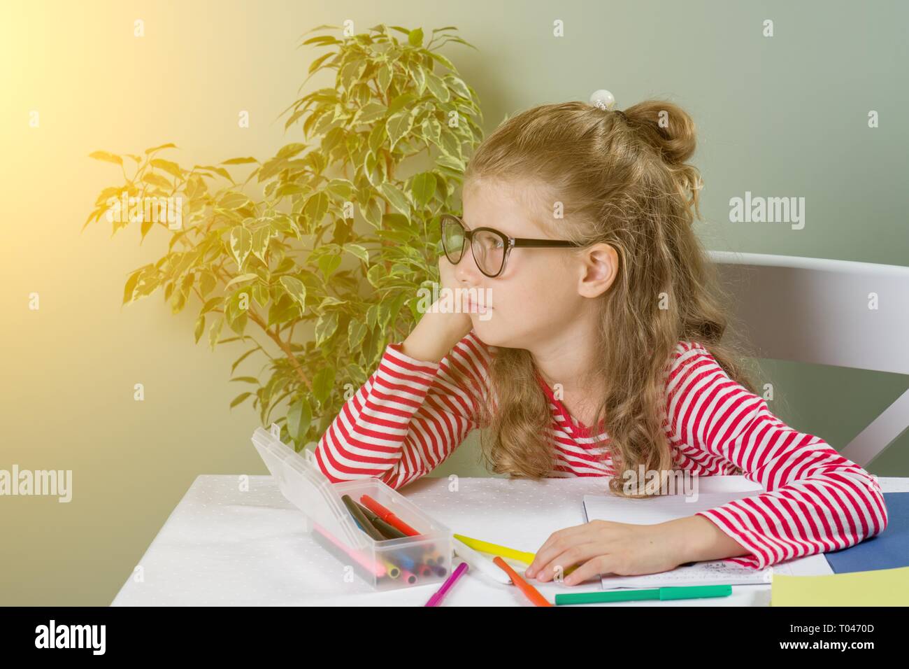 Sad and tired cute junior schoolgirl with blond hair sitting in stress ...