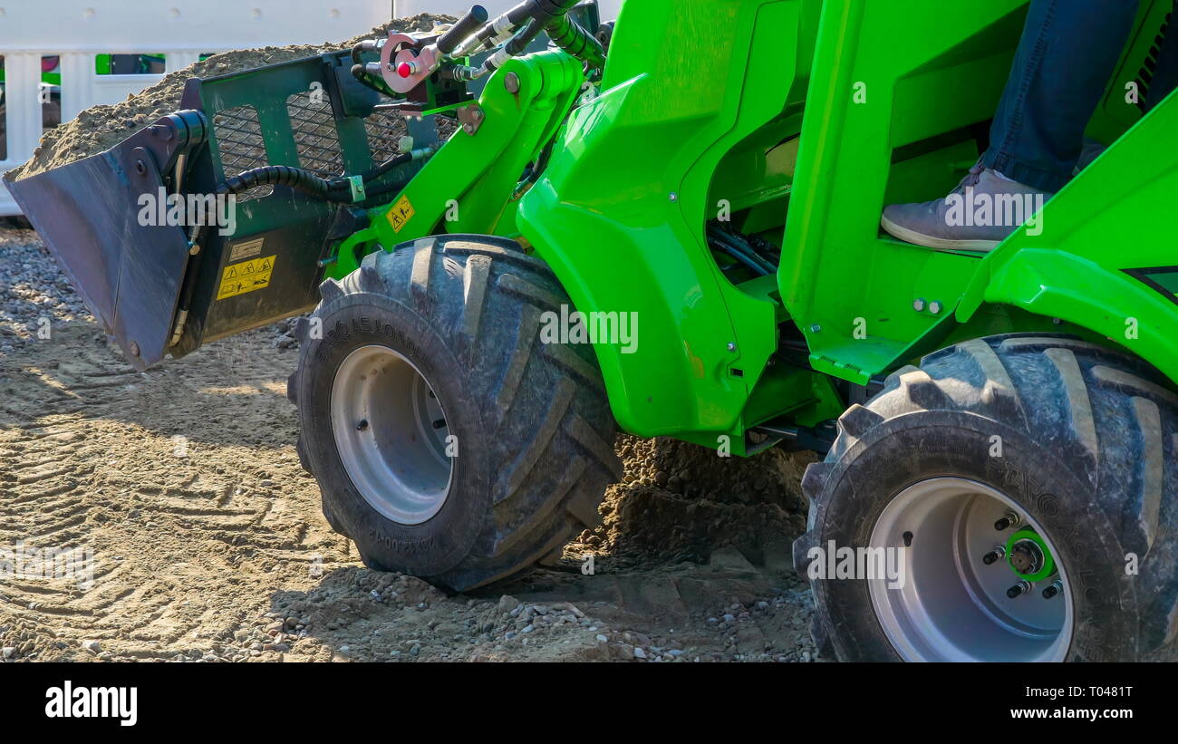 The green bulldozer getting big heaps of brown soil from the ...