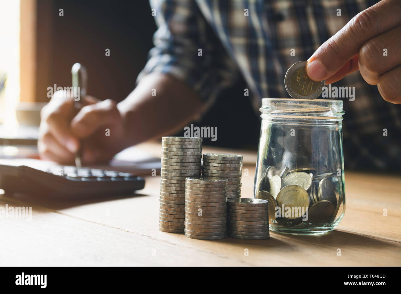 Hand putting money in jar hi-res stock photography and images - Alamy