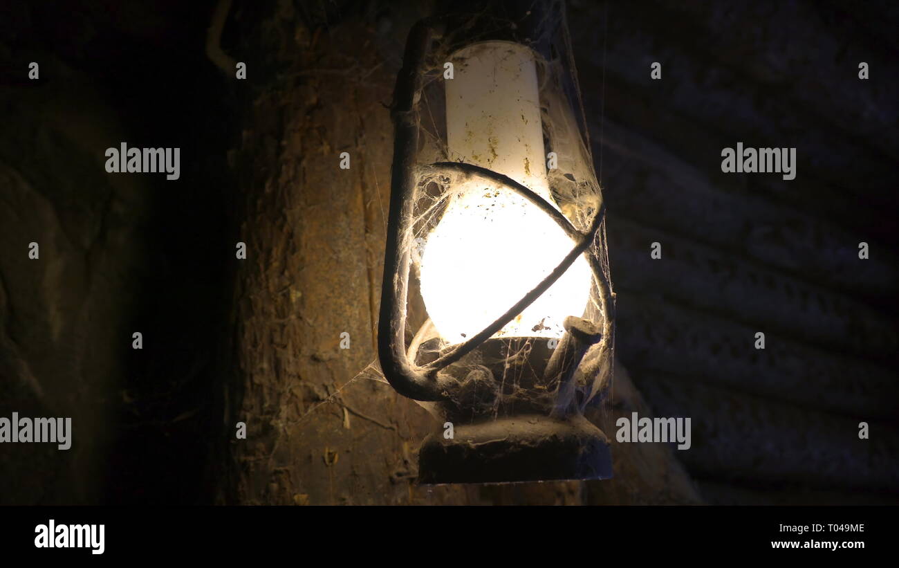 Dirt dust and cobwebs on the lighted lamp inside an old wooden house ...