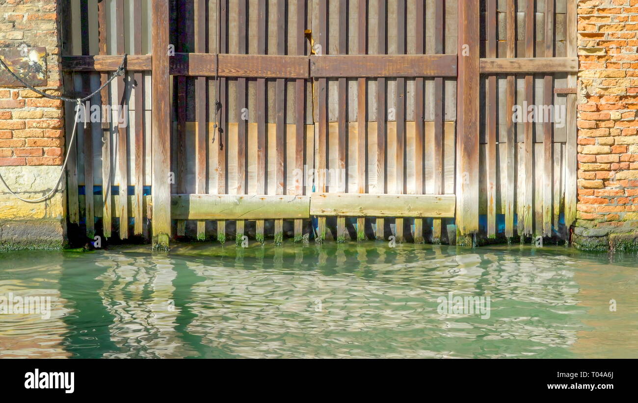 The wooden big gate of the building in the side of the canal with the ...