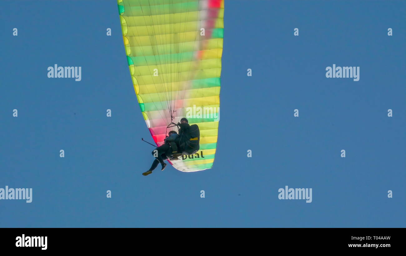 The green parachute about to land on the ground gliding on the sky on a ...