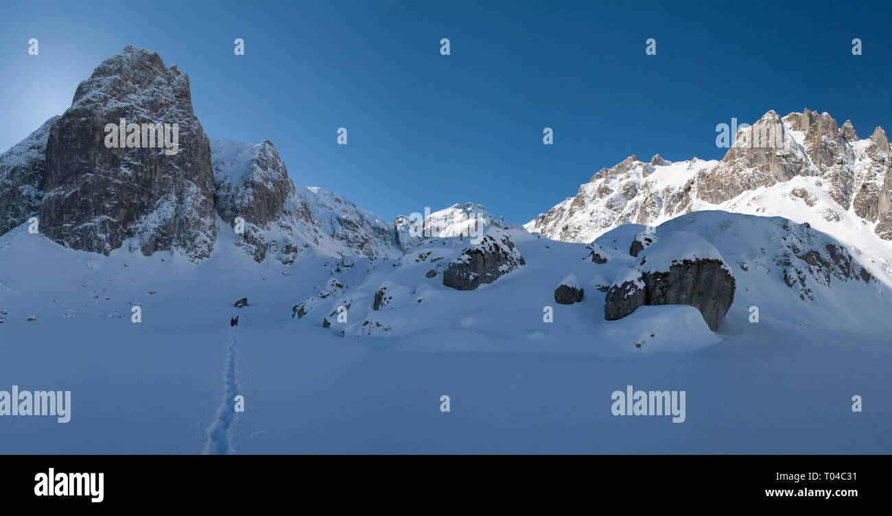 Mountain valley with people walking and path in the snow Stock Photo ...
