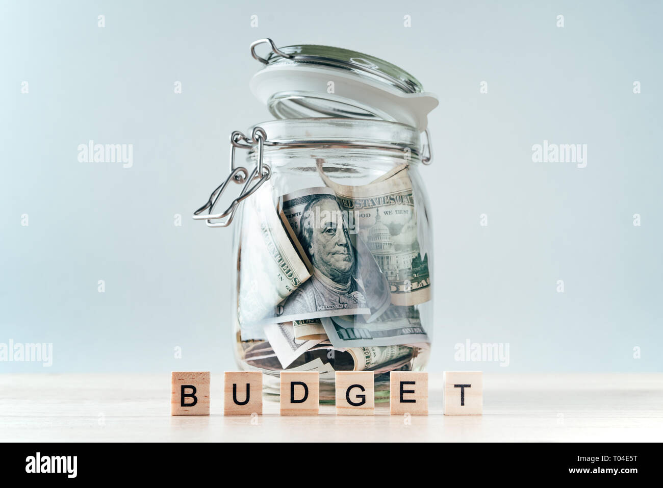 us dollars bill in glass jar and word budget made of wooden blocks ...