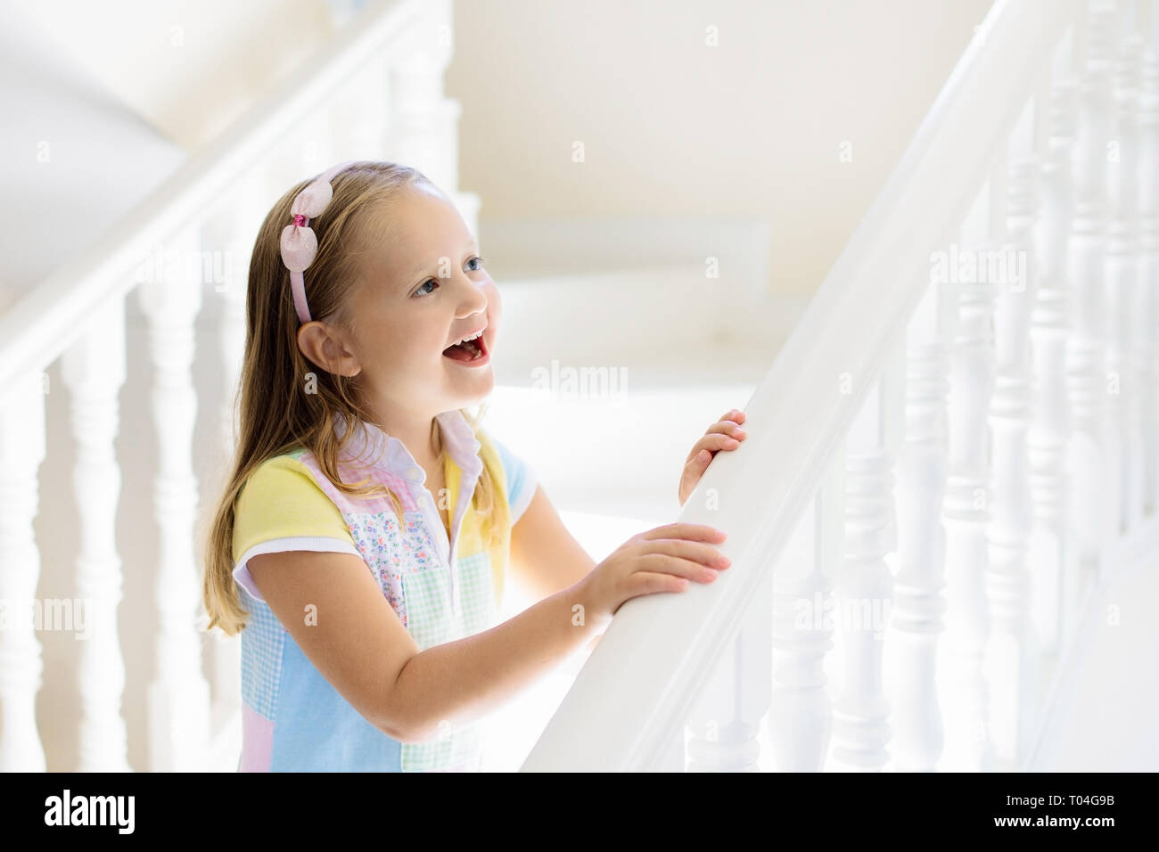 Kid walking stairs in white house. Little girl playing in sunny ...