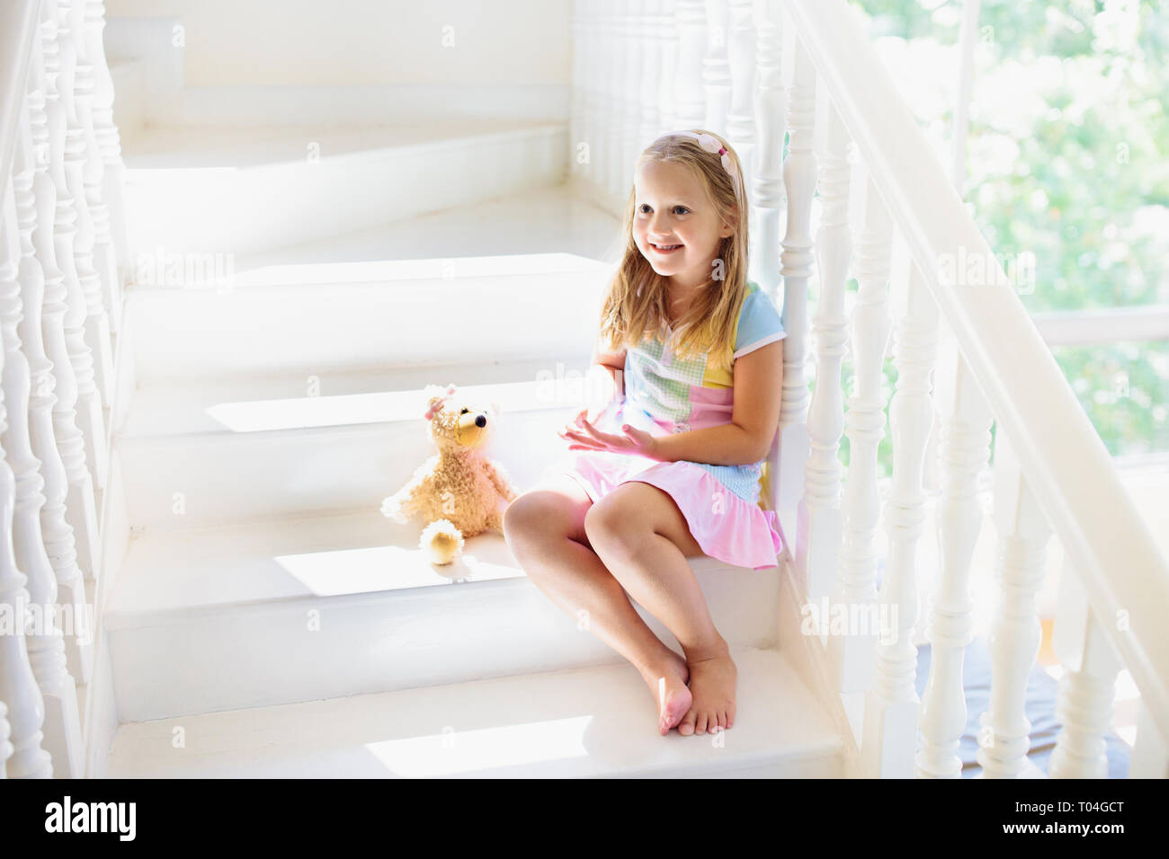 Kid walking stairs in white house. Little girl playing in sunny ...