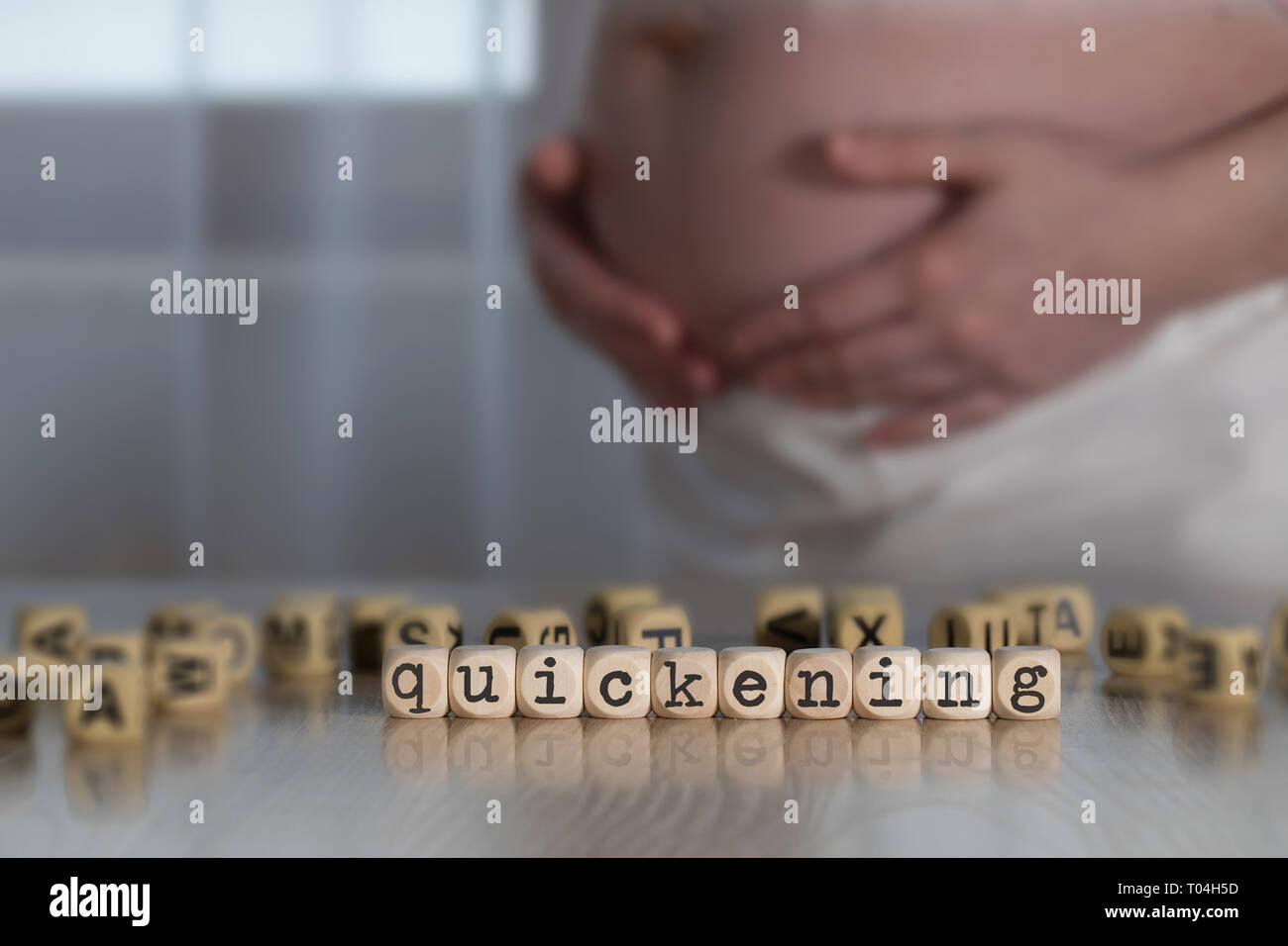 Word QUICKENING composed of wooden letters. Pregnant woman in the ...