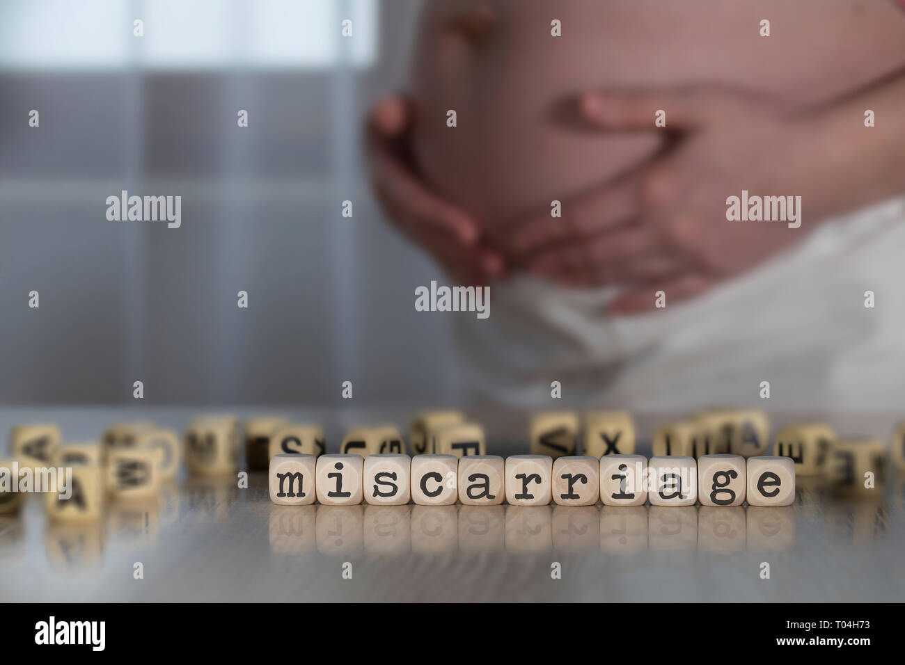 Word MISCARRIAGE composed of wooden letters. Pregnant woman in the ...