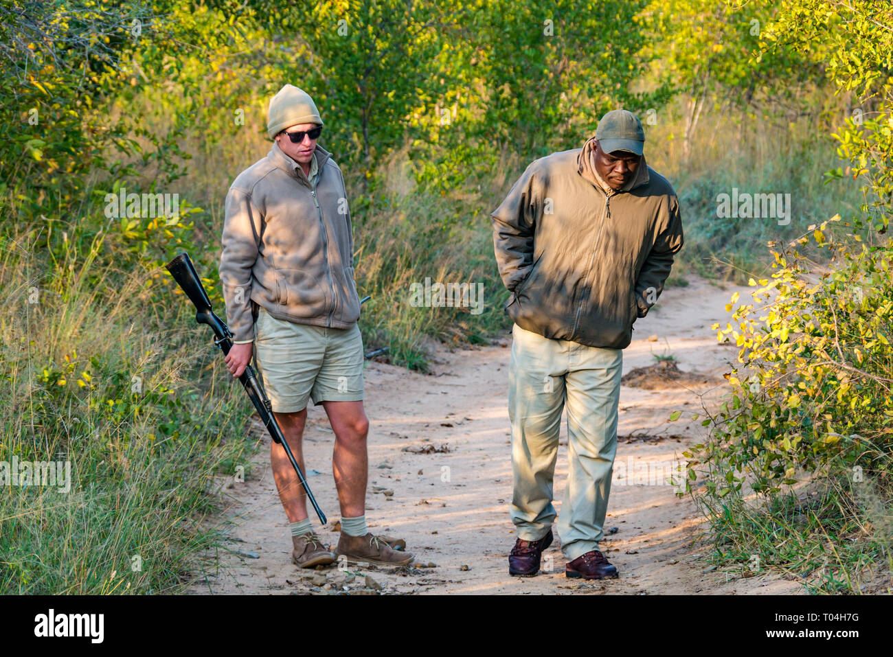 Guide with rifle and Black man tracker looking for animal tracks in ...