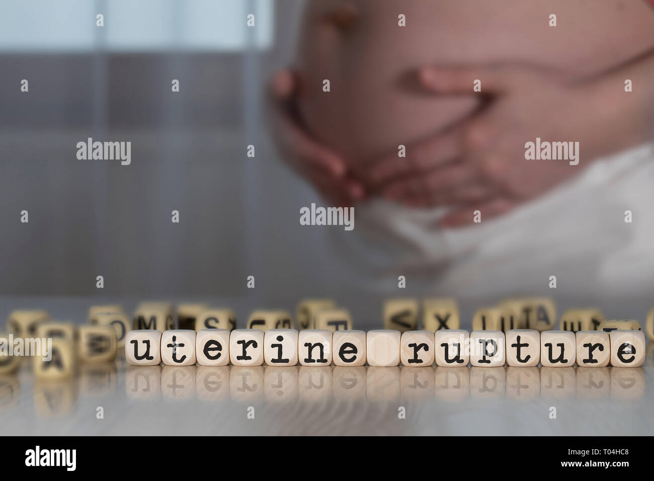 Words UTERINE RUPTURE Composed Of Wooden Letters Pregnant Woman In The Background Stock Photo words-uterine-rupture-composed-of-wooden-letters-pregnant-woman-in-the-background-stock-photo