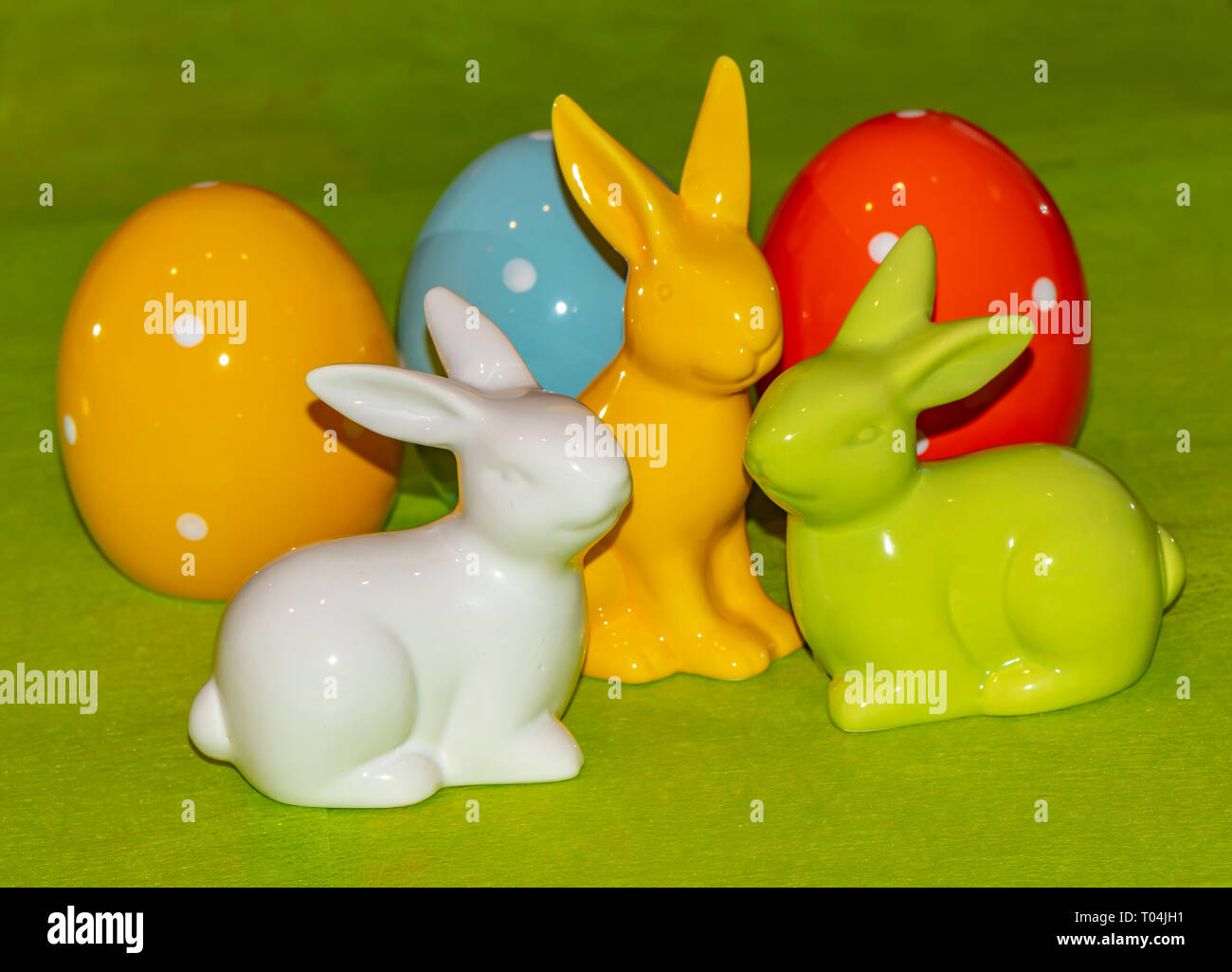 Colorful ceramic easter eggs and Easter bunnies in front of a green ...