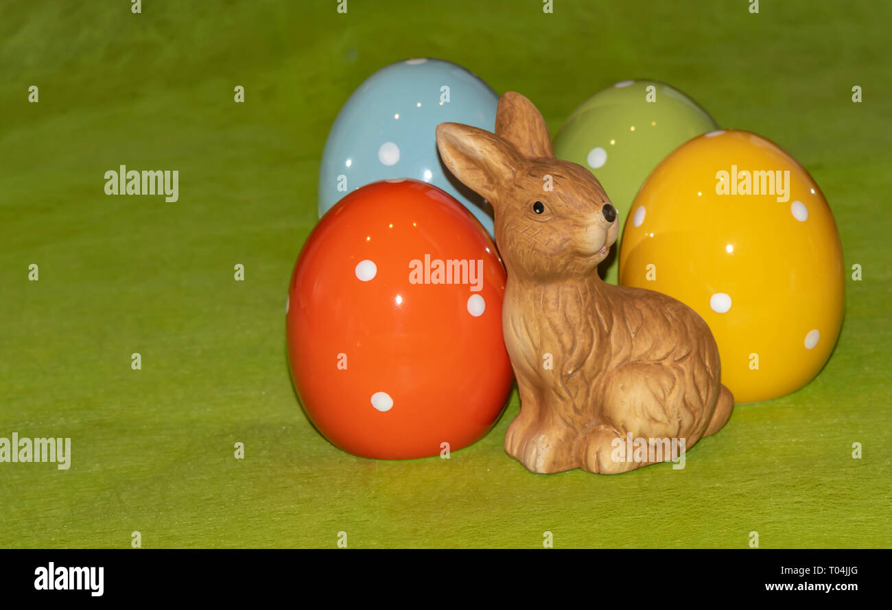 Colorful ceramic easter eggs and an Easter bunny in front of a green ...