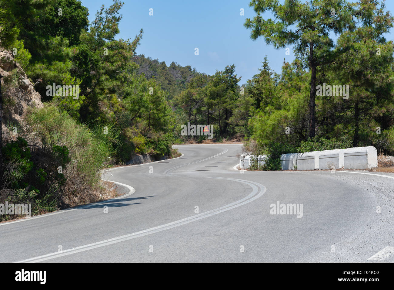 Down a curvy, bendy road. Open road through forest on hillside. Open ...