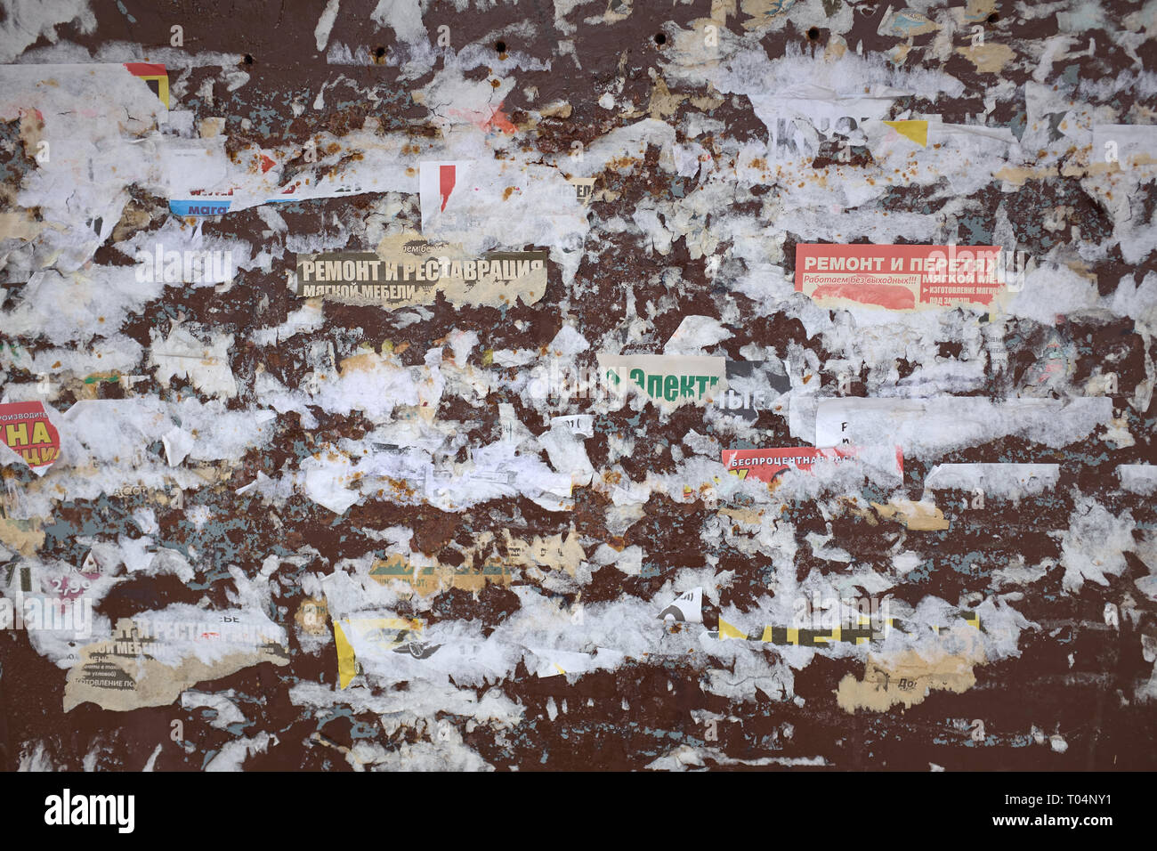 Torn posters on rusted steel wall. A lot of the torn-off announcements ...