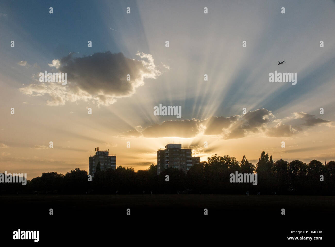 Rays of light from an urban sunset with tower blocks in the foreground ...