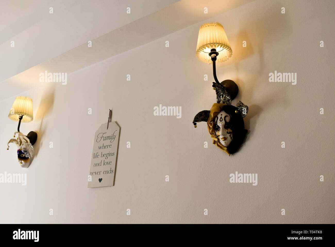 Carnival masks hanging under wall light lamps, indoor decorations Stock ...