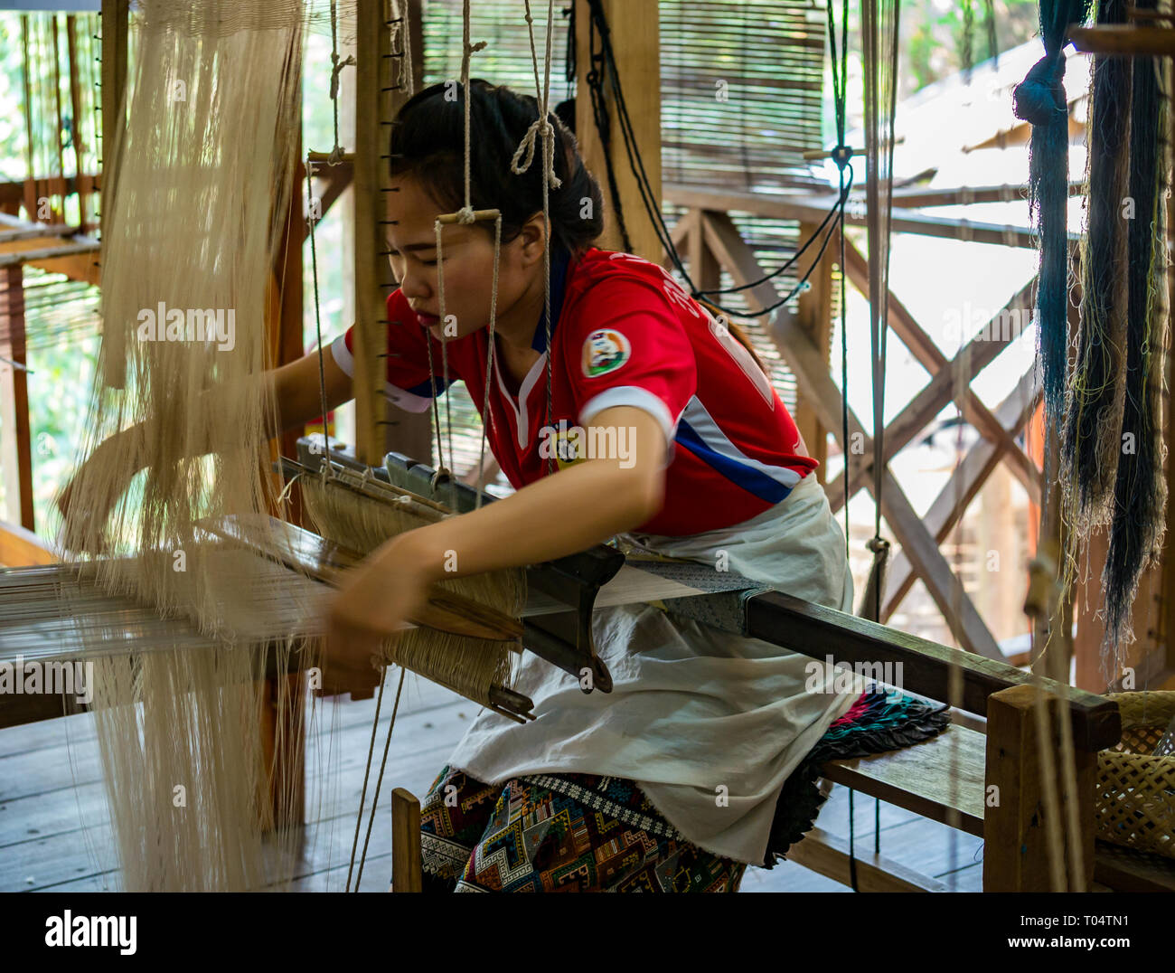 Female worker weaving textile on loom at cooperative workshop, Luang ...
