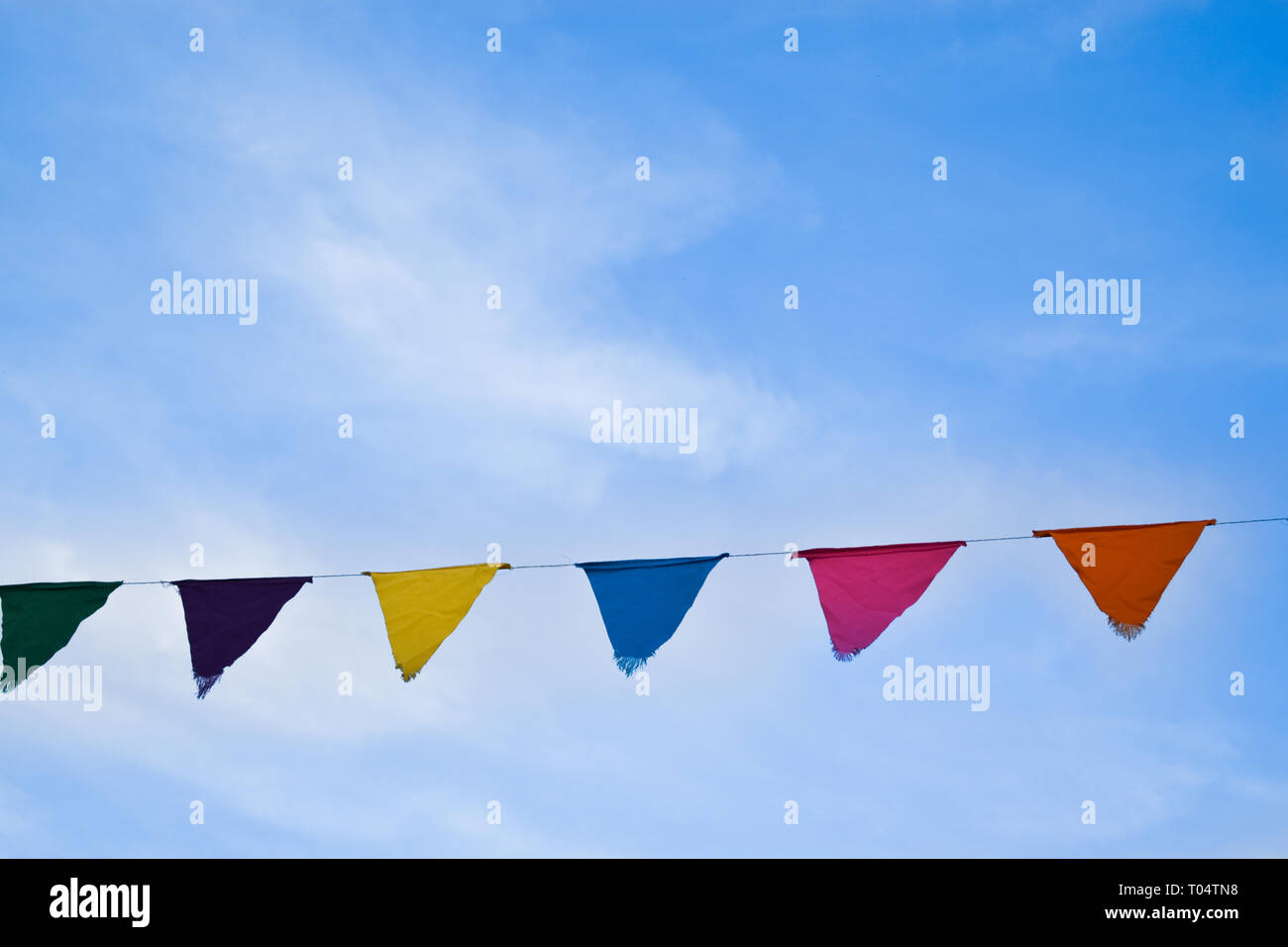 Colored triangular flags on bright blue sky background, festive ...