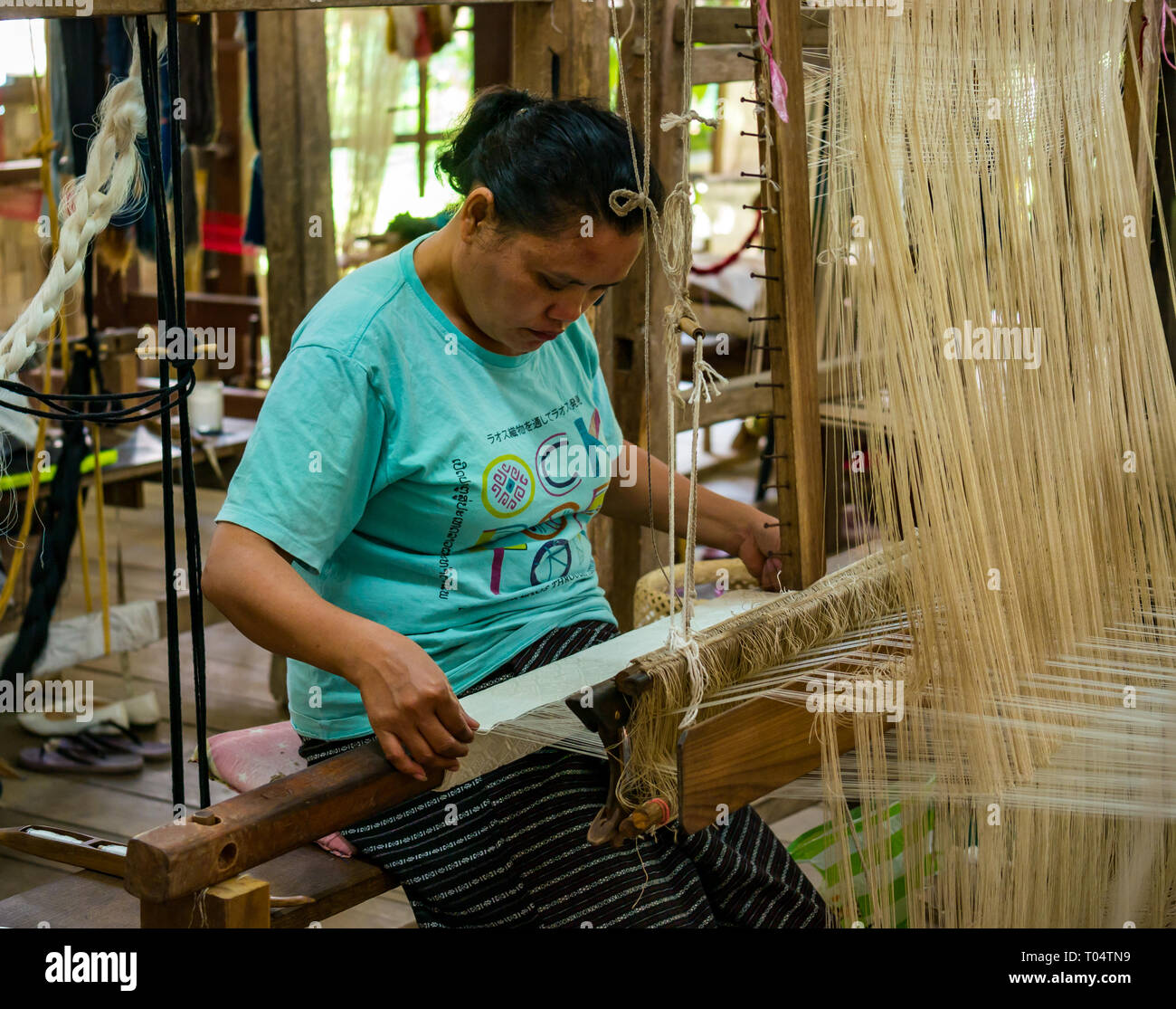 Female worker working on weaving textile on loom, Ock Pop Tok weaving workshop, Luang Prabang ...