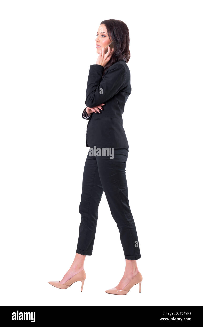 Side view of busy business woman walking and communicating on cellphone ...