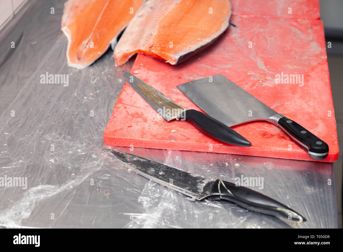 Closeup carving whole fresh norwegian salmon fish with knife on red ...