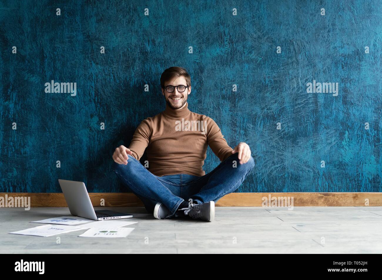 Man sitting on the floor with laptop computer in studio. Isolated on ...