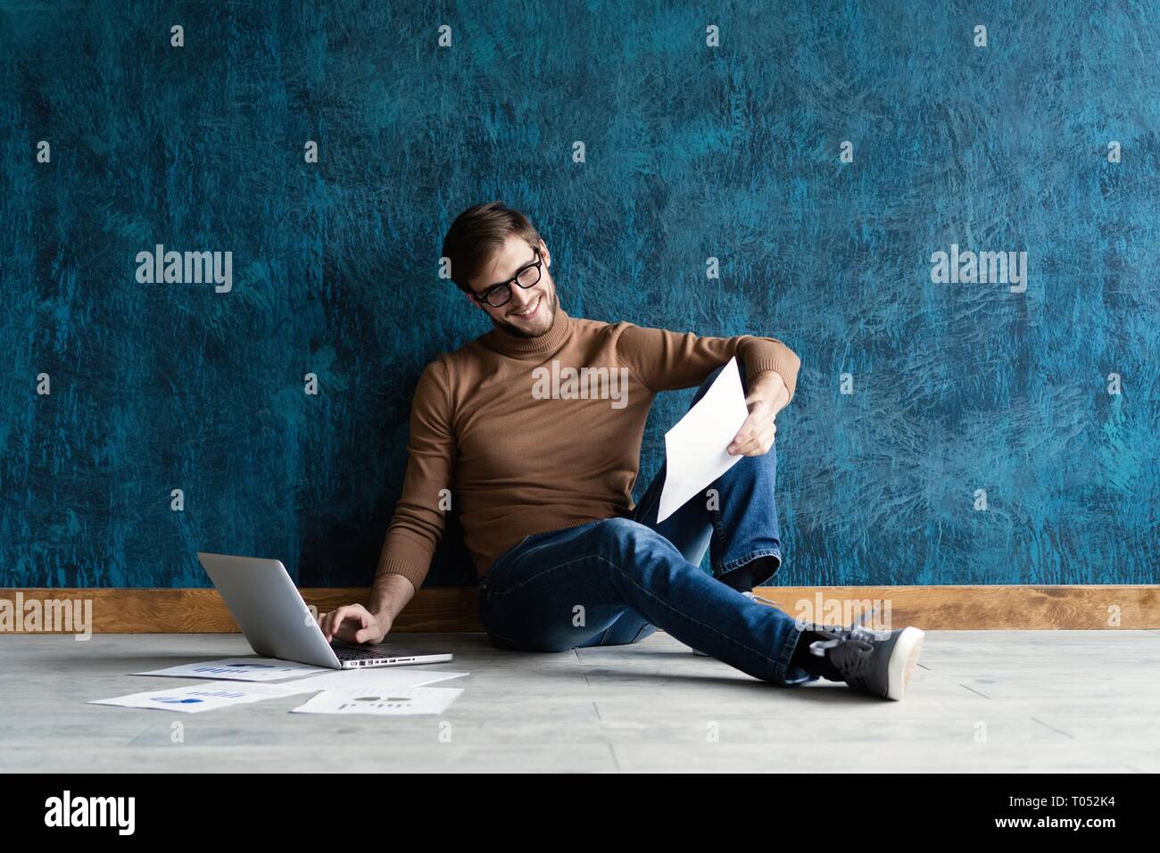 Man sitting on the floor with laptop computer in studio. Isolated on ...