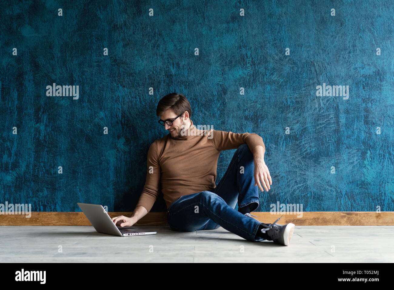 Man sitting on the floor with laptop computer in studio. Isolated on ...