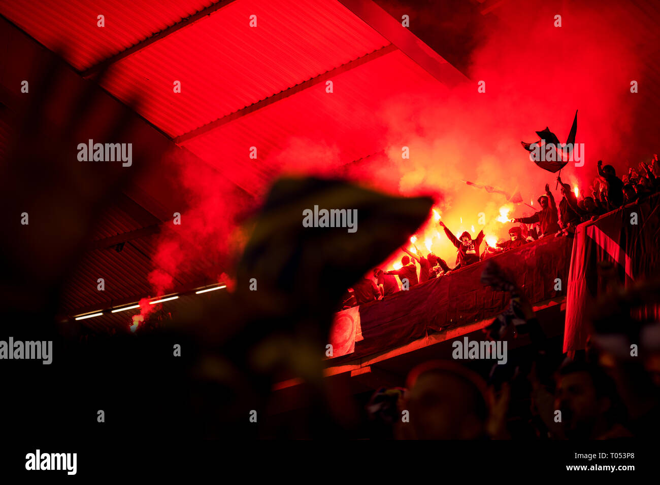 football hooligans with mask holding torches in fire while supporting ...