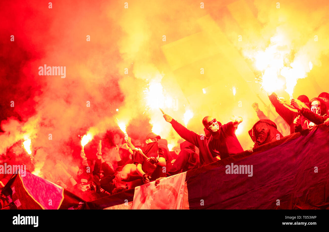 football hooligans with mask holding torches in fire while supporting ...